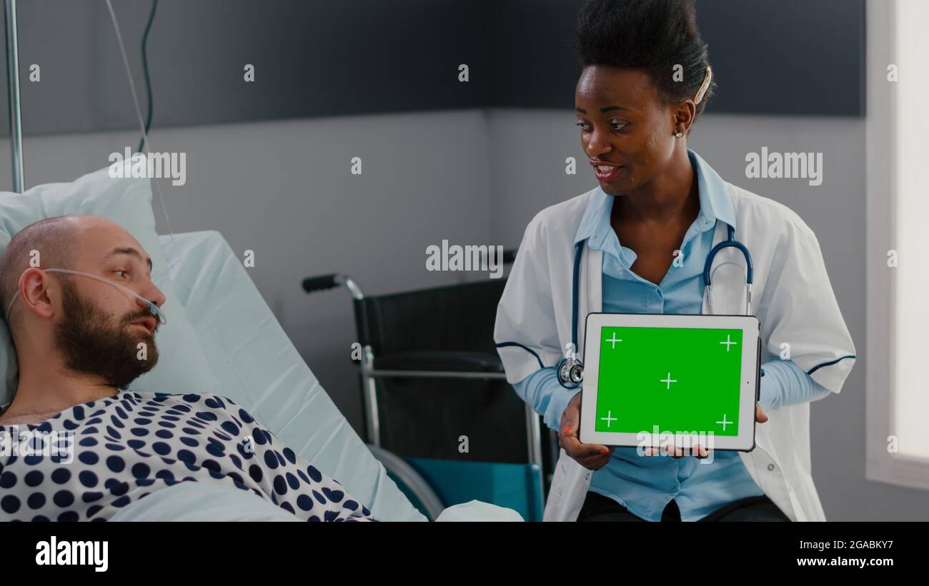 Doctor with dark skin explaining to woman patient resting in bed about ...