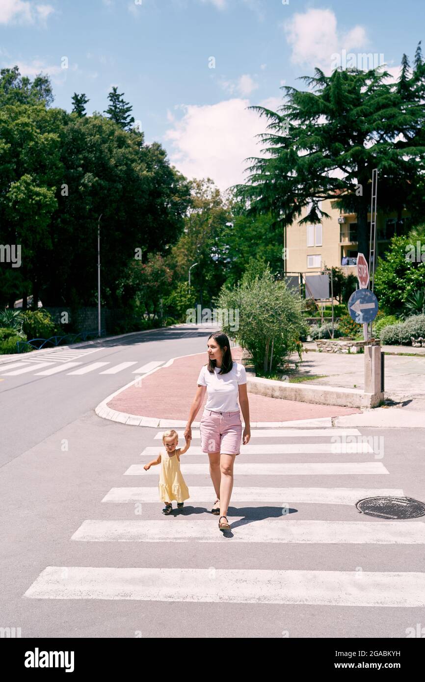 Mom leads the girl along the zebra crossing across the road Stock Photo ...