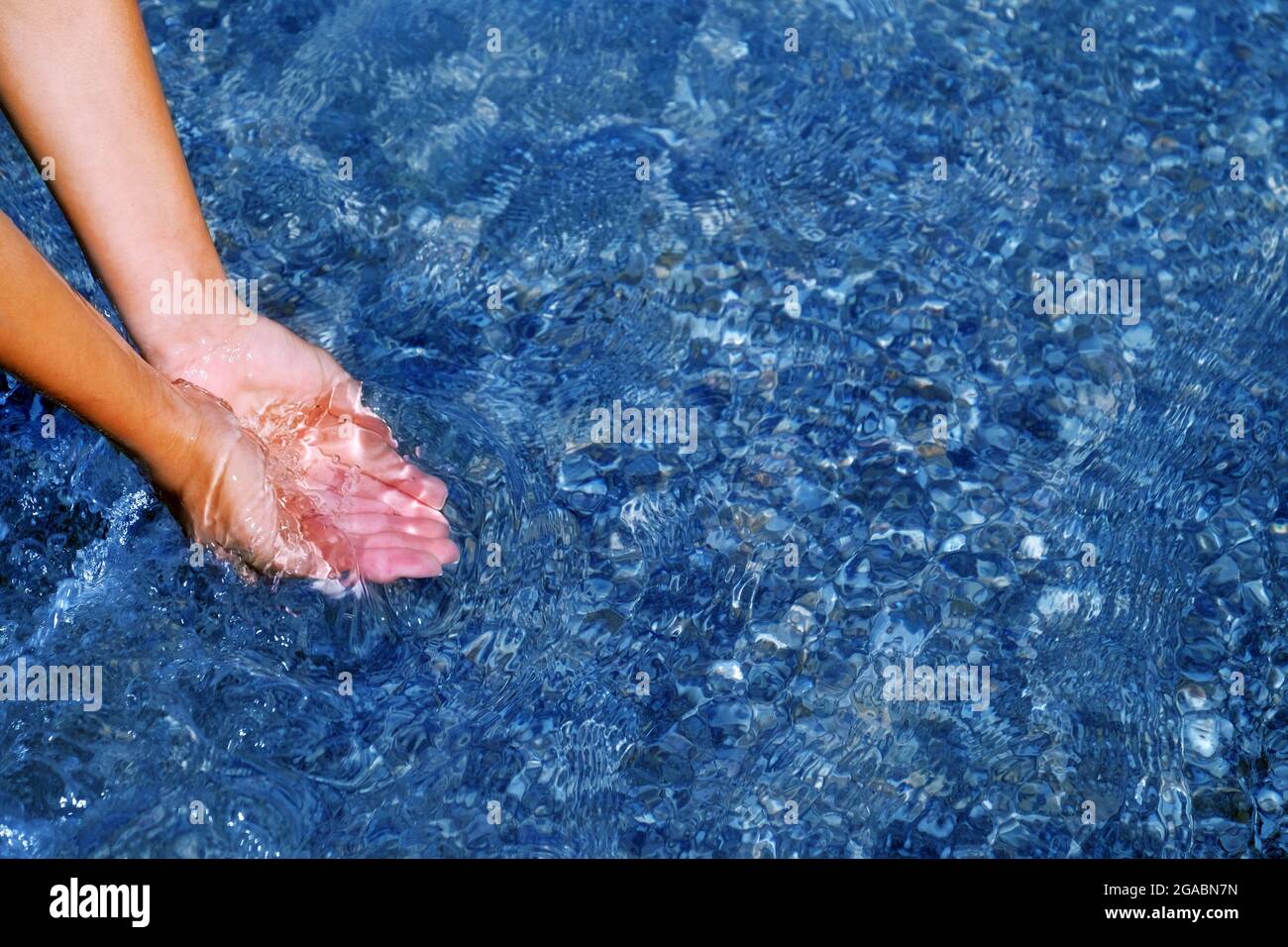 Womans hand touching the blue water Stock Photo - Alamy