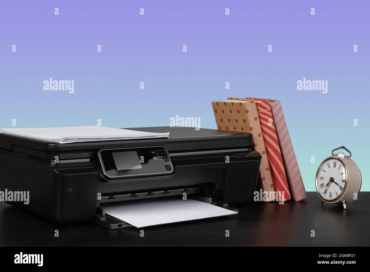 Home laser printer on desk against purple background Stock Photo - Alamy