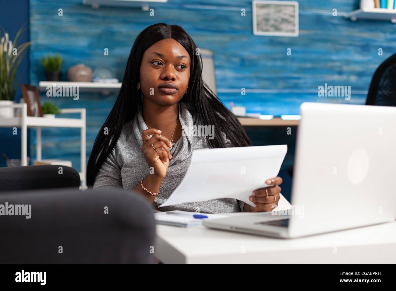 Black woman looking at accounting strategy on monitor using laptop ...