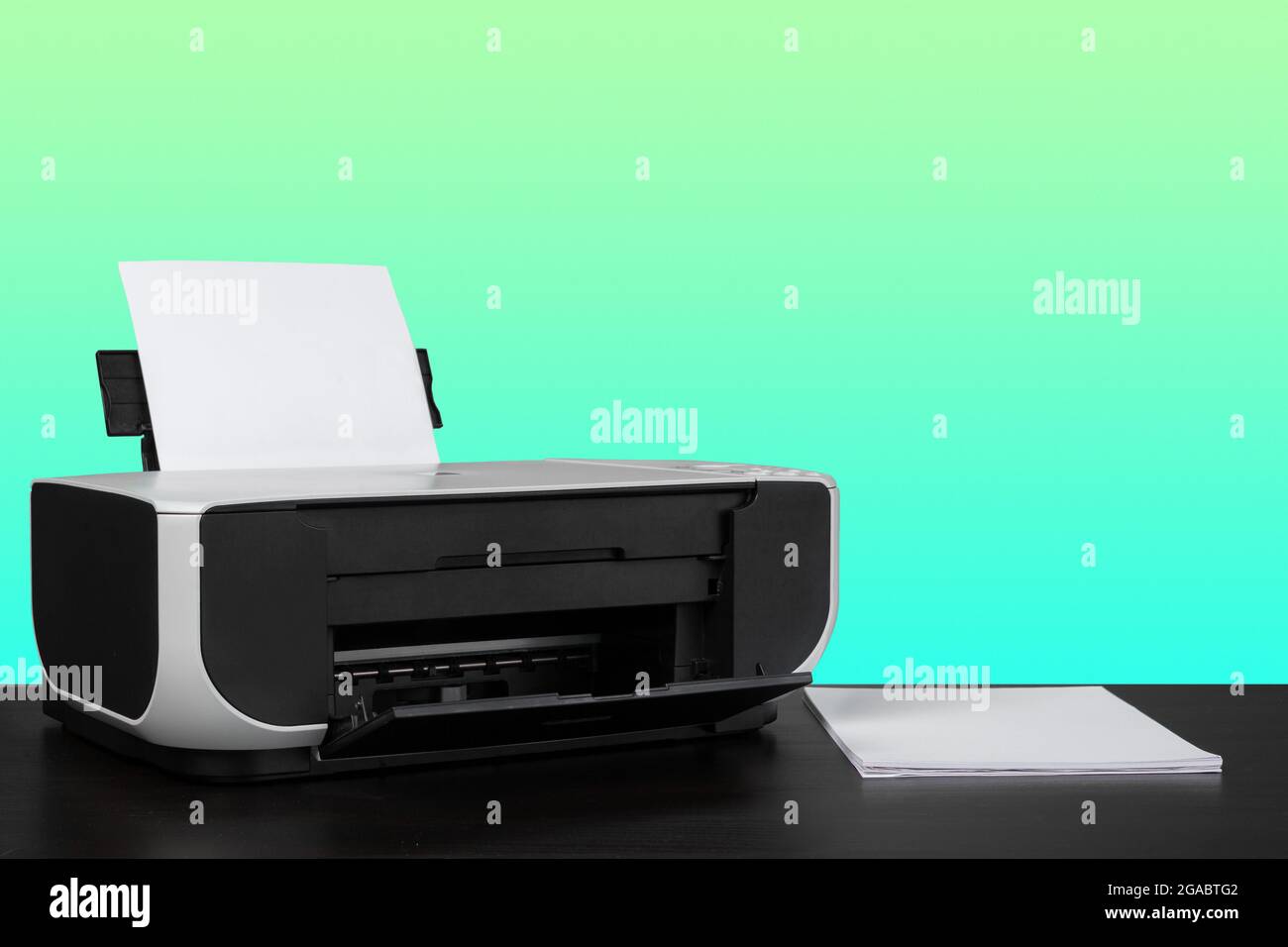 Home laser printer on desk against green background Stock Photo - Alamy