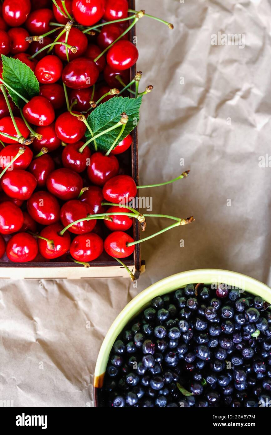 Cropped bowl of blueberries and box, crape of red sweet cherries with ...