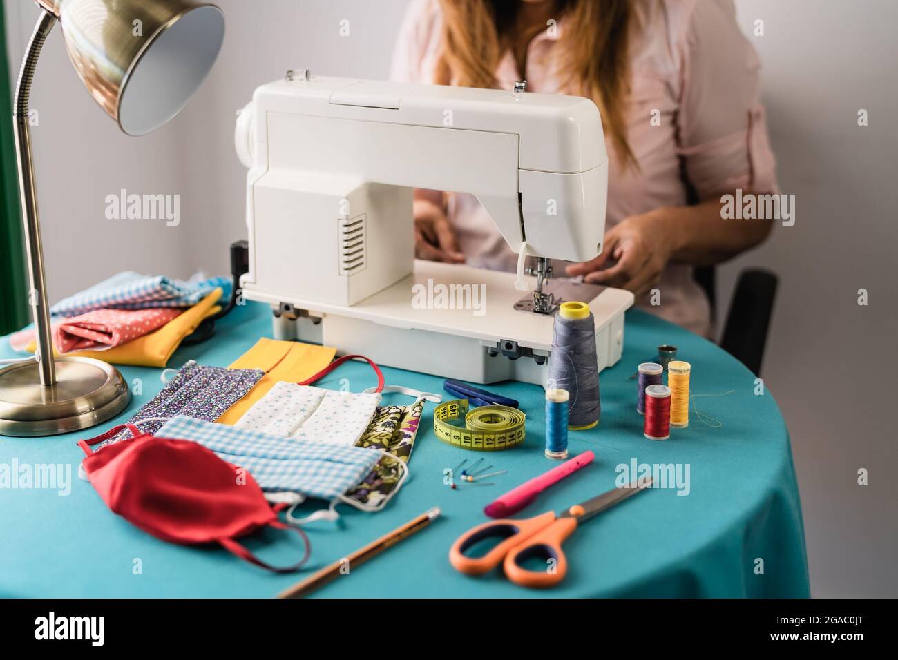 Female working with sewing machine doing homemade face mask for ...