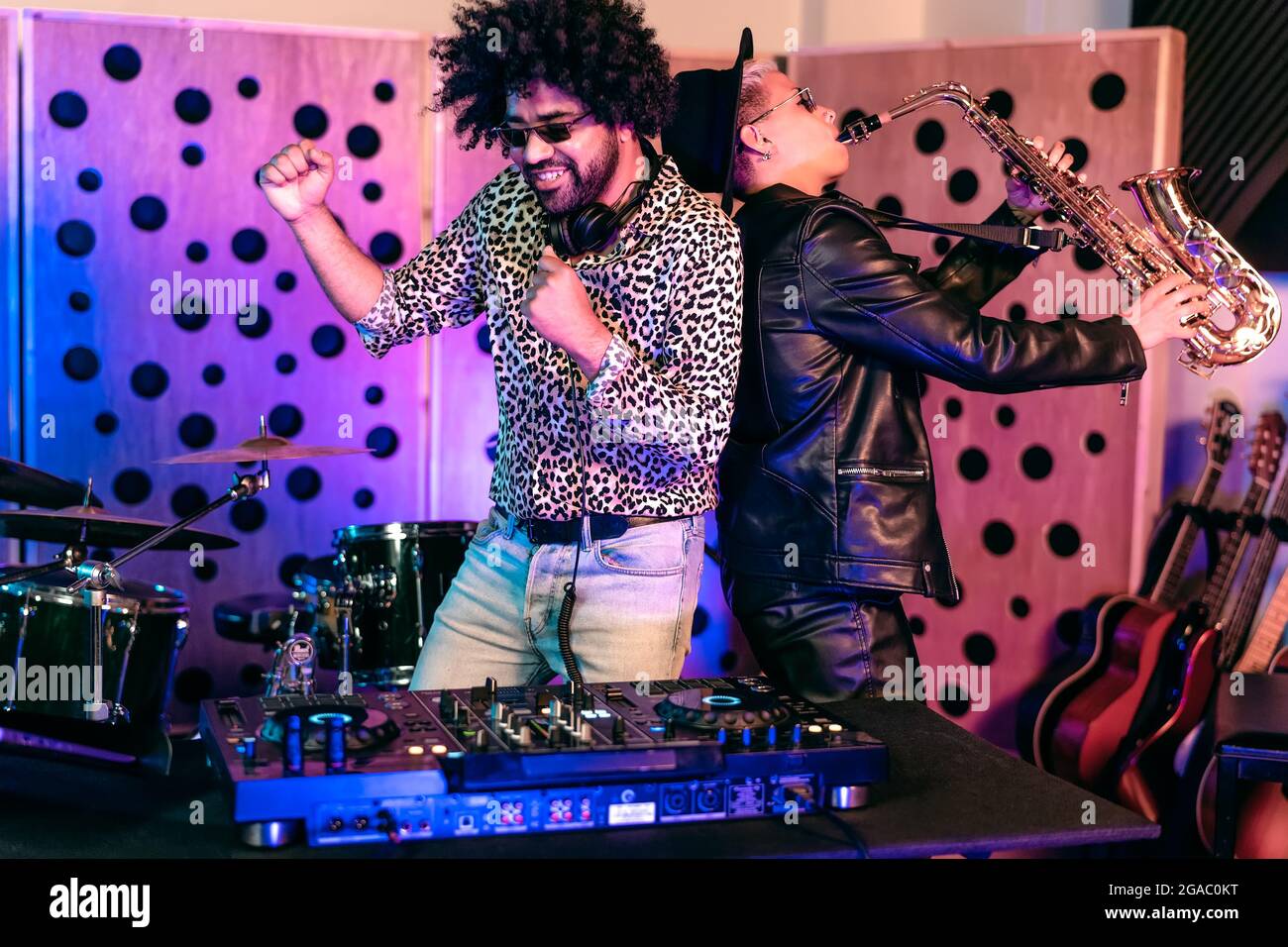 Young happy people playing music with dj mixer and saxophone in house ...