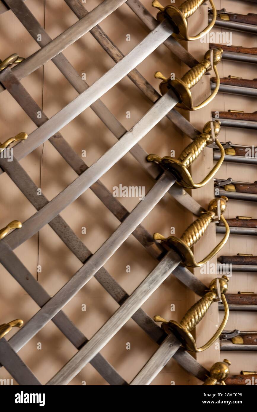 large number of antique cavalry or infantry swords hanging on a wall in ...
