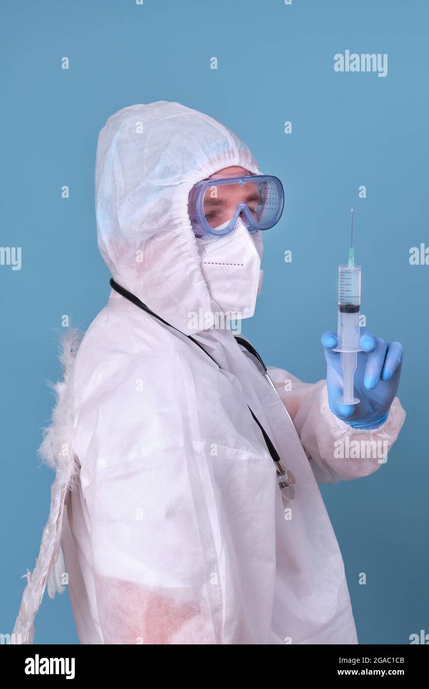 A paramedic in angel wings with a vaccination syringe on a blue ...