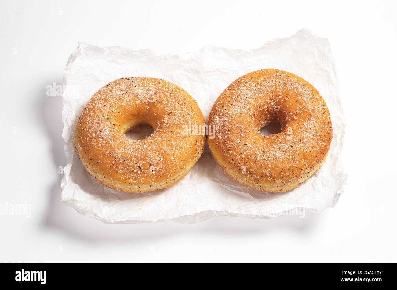 Two fresh classic donuts in crumpled paper on white background Stock ...