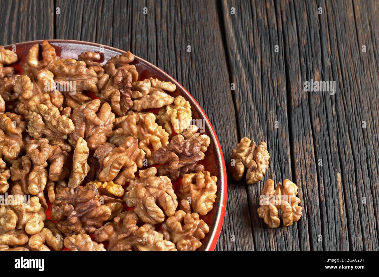 Walnut kernels in red plate on old wooden table with space for text ...