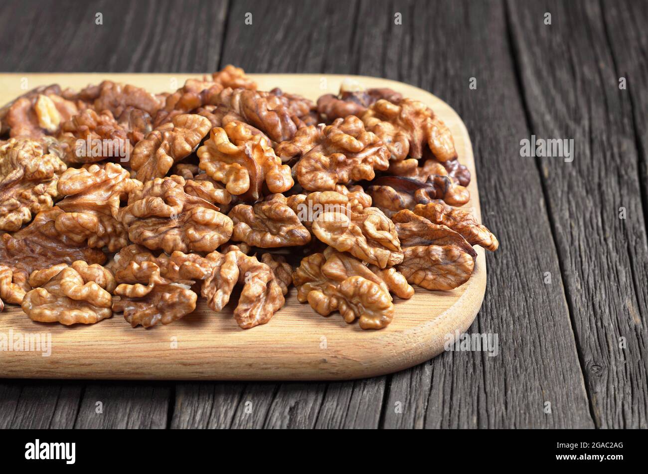 Walnut kernels on cutting board on dark wooden table. Healthy eating ...