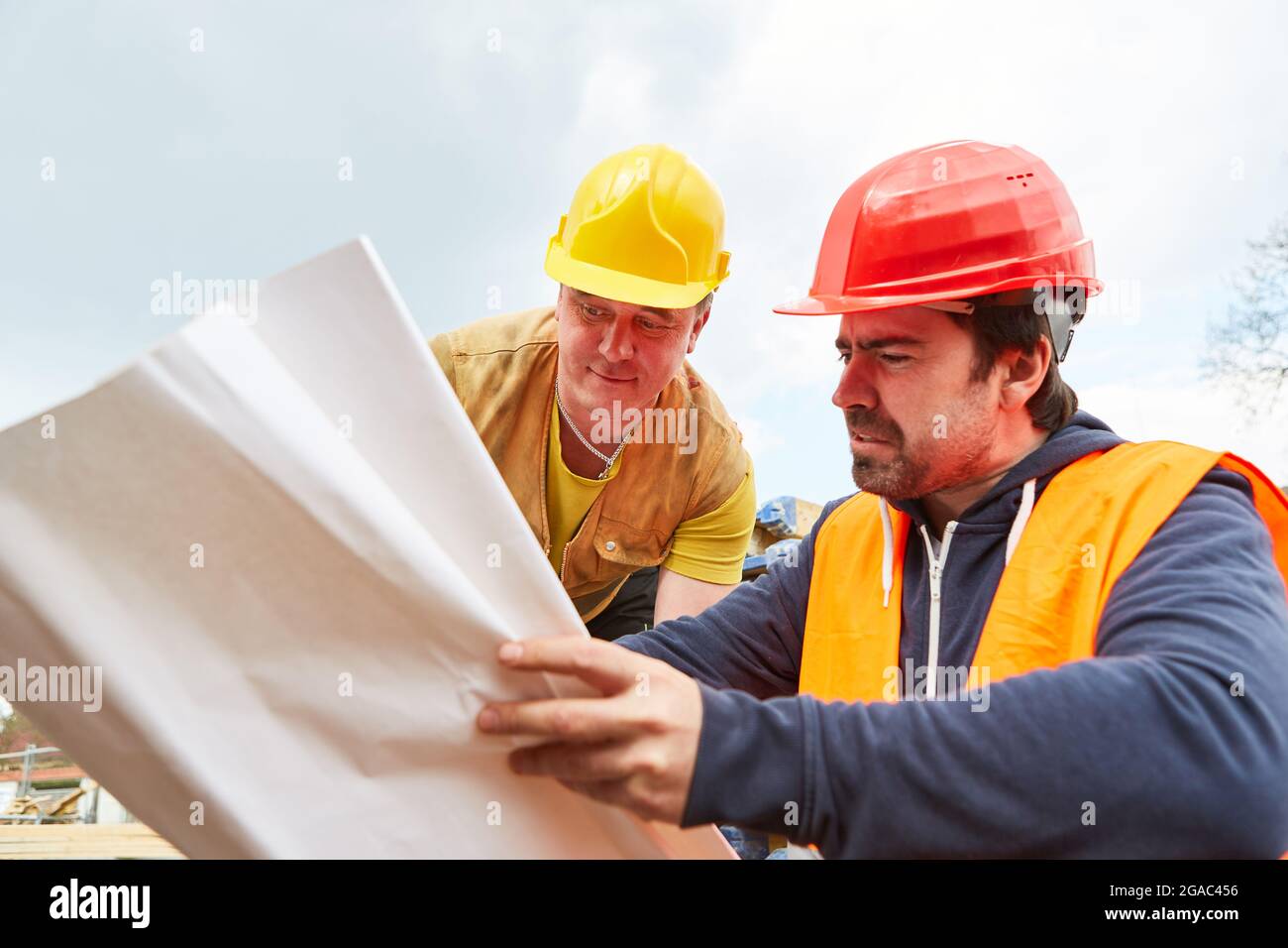 Construction worker and architect look together at architectural ...