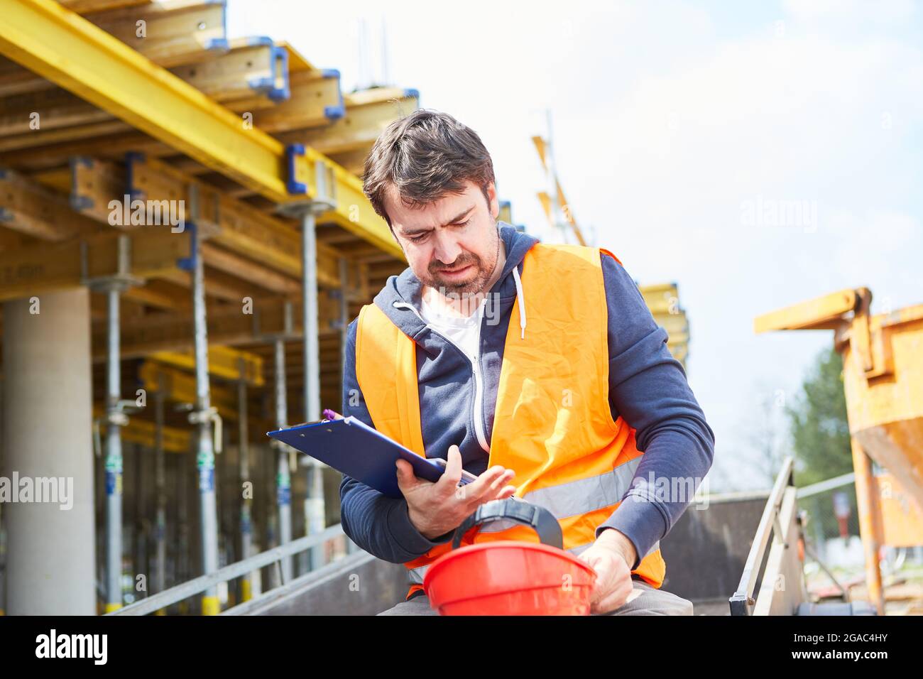 Thoughtful craftsman or construction worker with checklist on clipboard ...