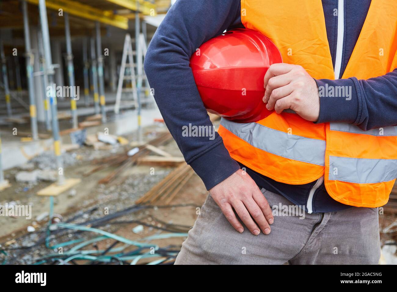 Worker on a construction site with red hard hat and reflective vest for ...