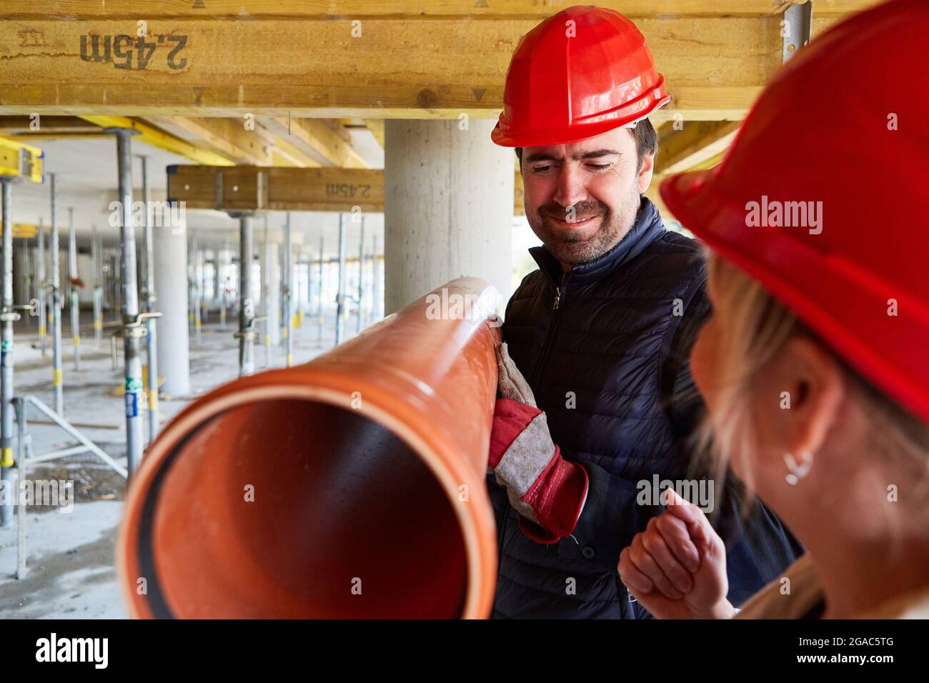 Craftsmen team transports a drain pipe for installation in the shell of ...