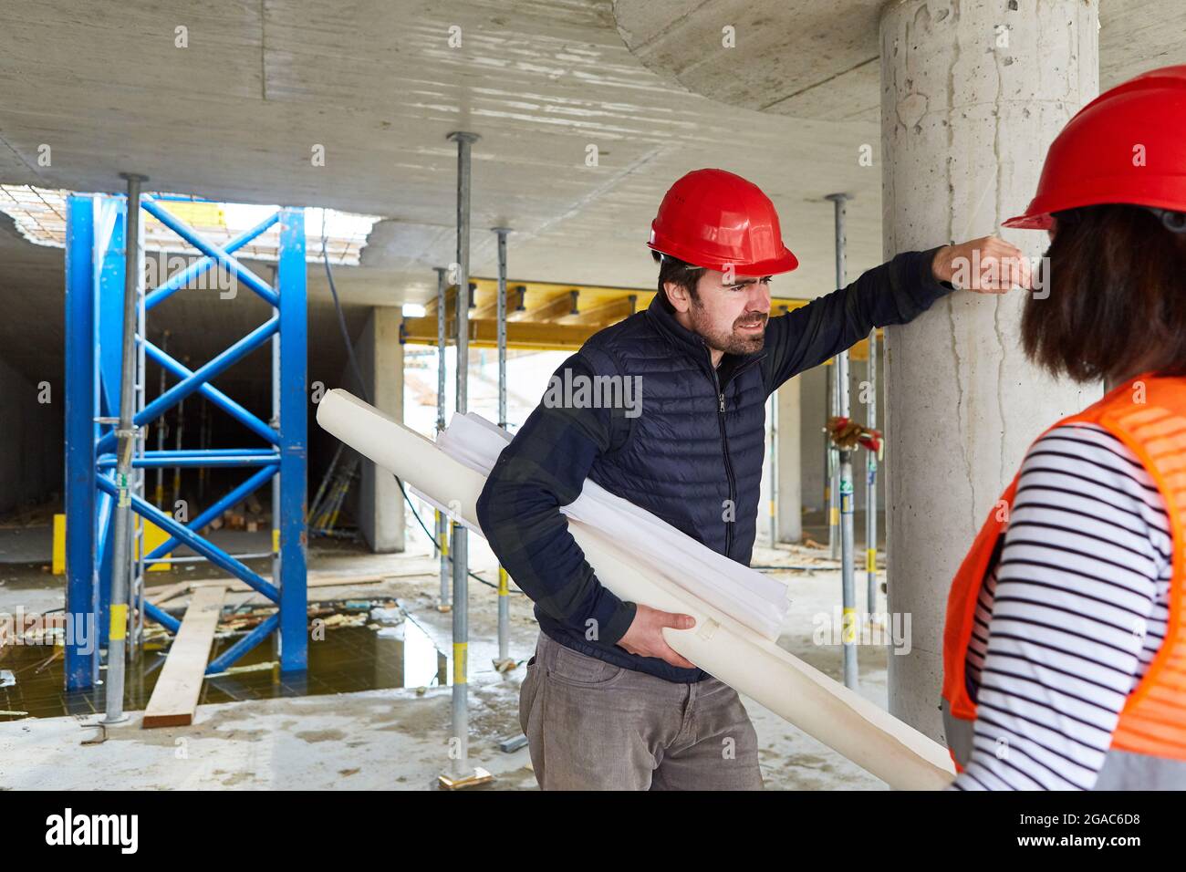 Architect with architectural drawing discusses construction work with ...