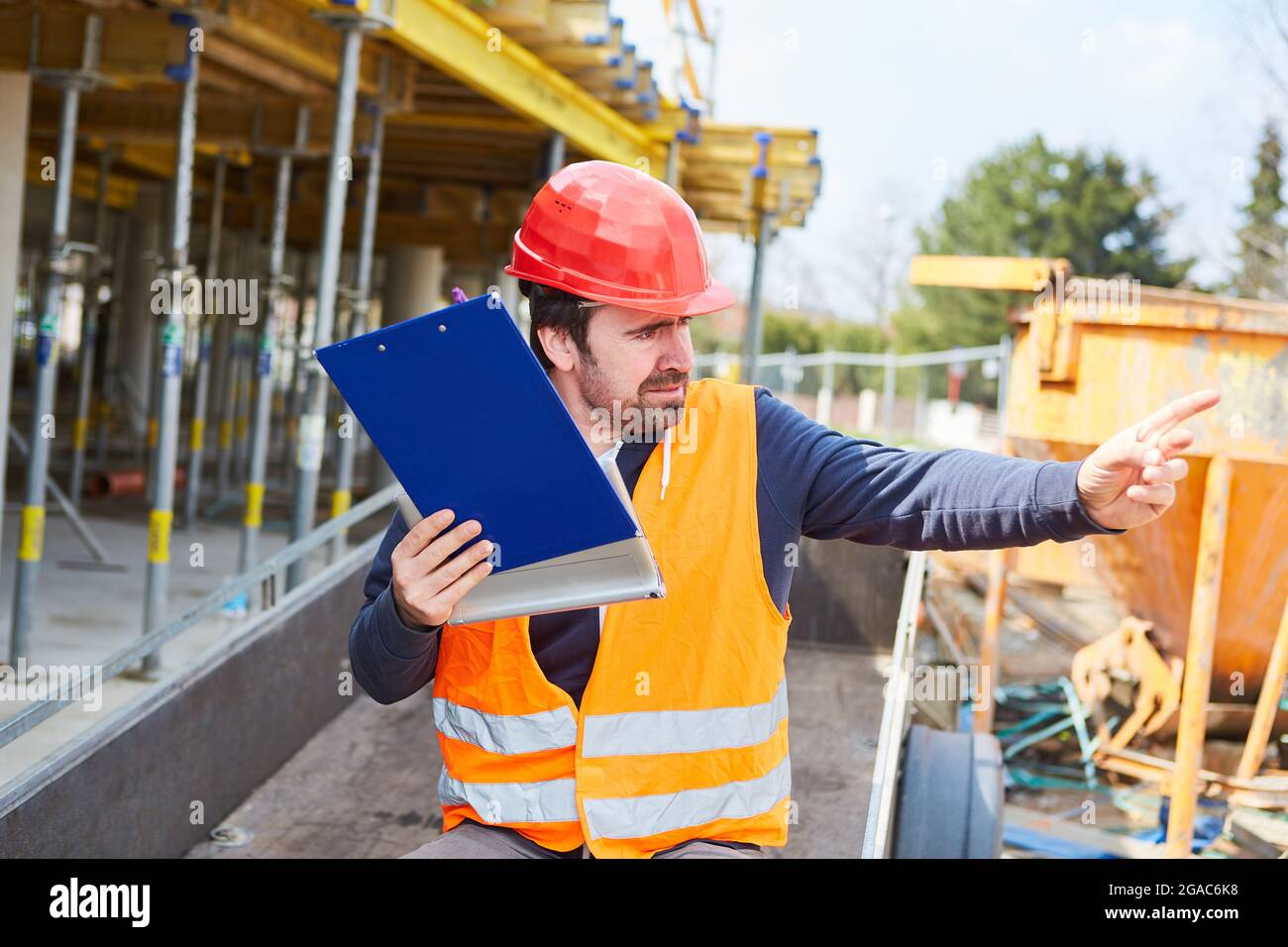 Foreman as site manager with checklist on clipboard gives instructions ...