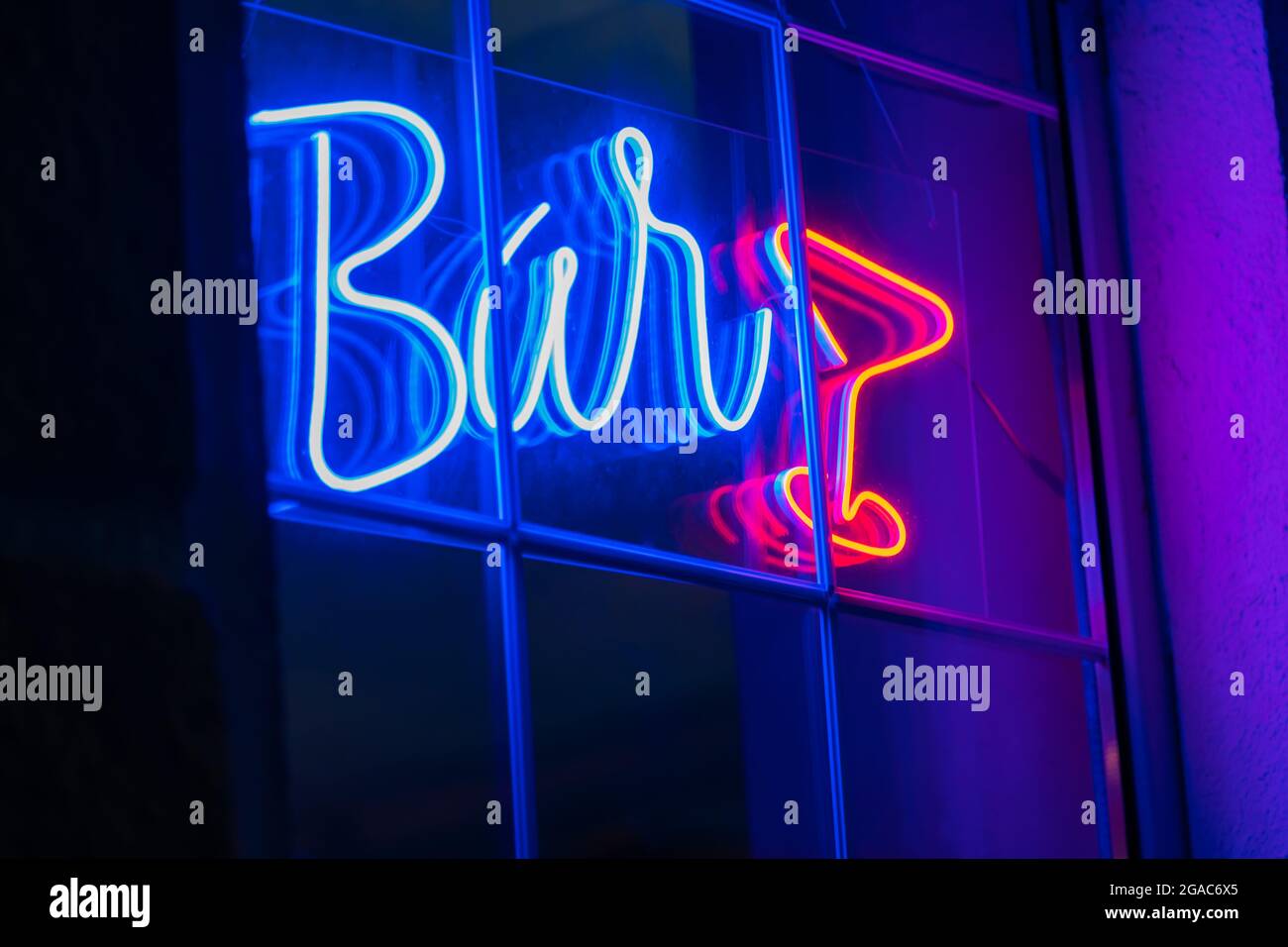 Beautiful blue neon bar sign with a red neon glass on the window ...