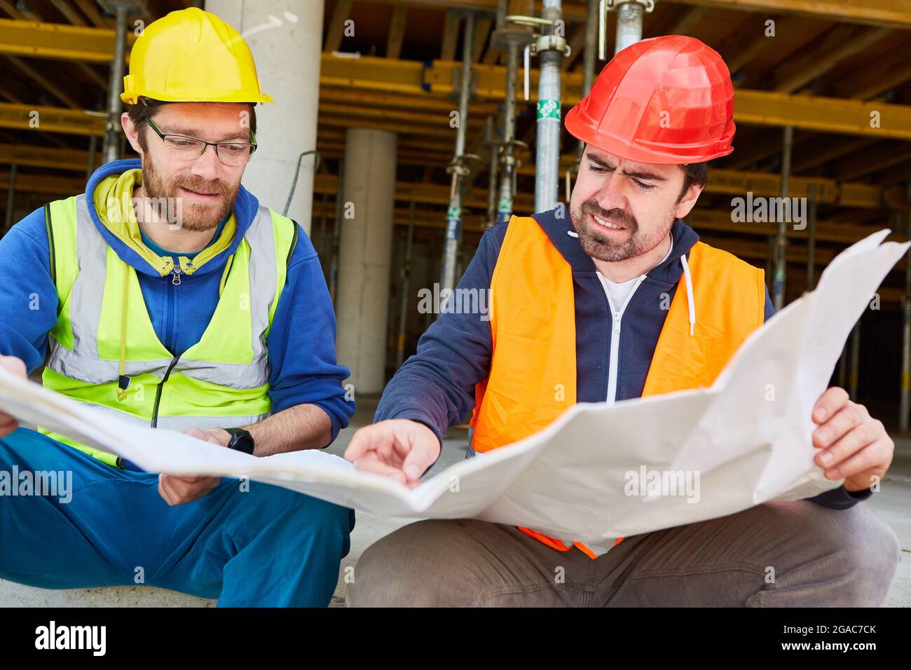 Architect and construction worker look together at an architectural ...