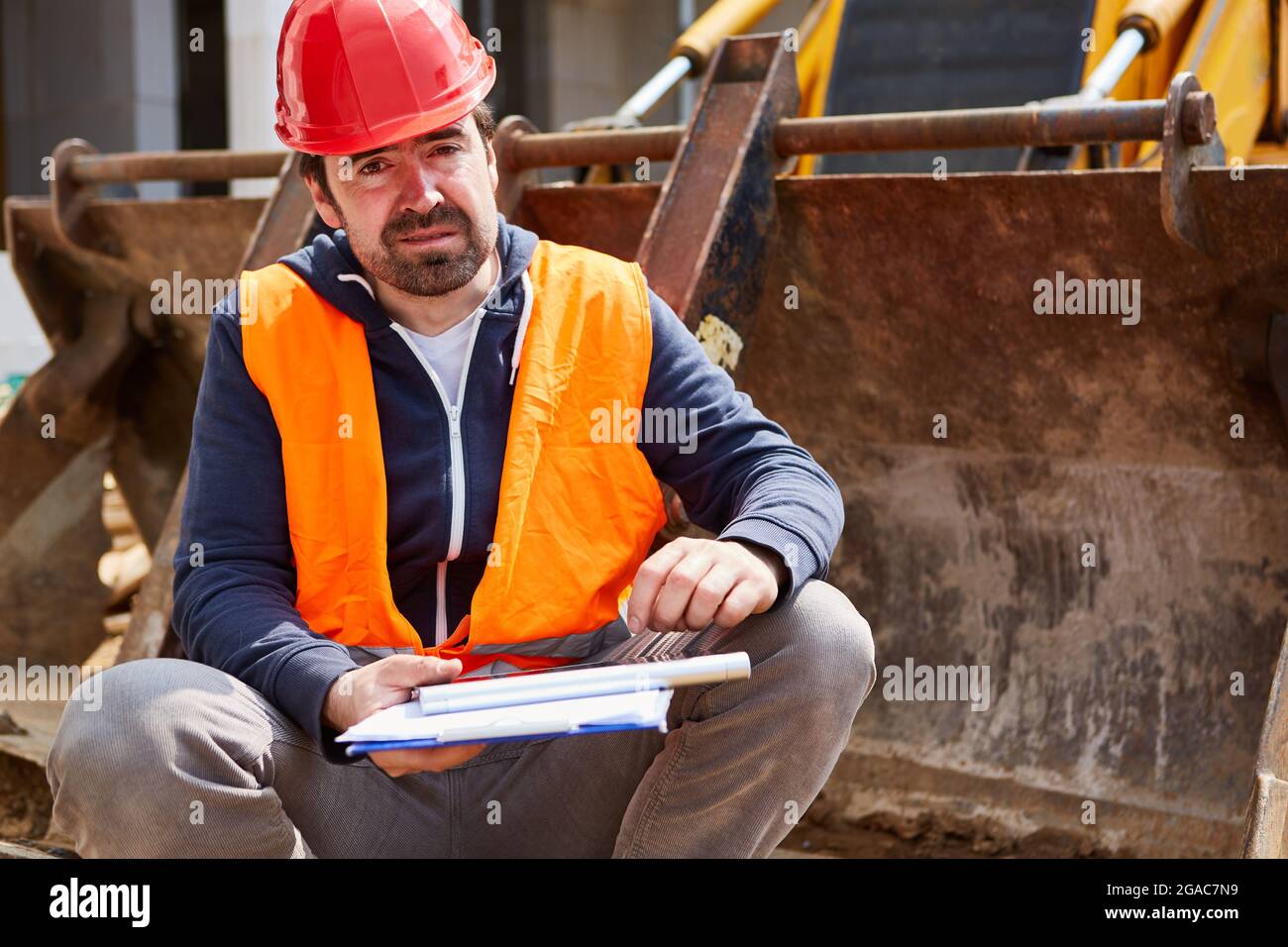 Craftsman or construction worker with checklist sitting on an excavator ...