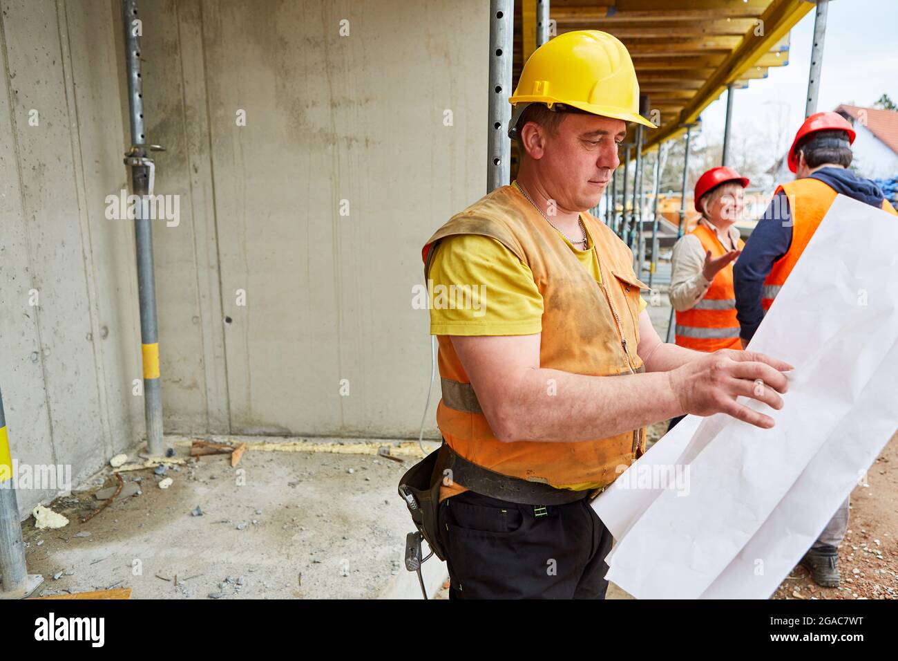 Foreman with architectural drawing and workers team on the construction ...