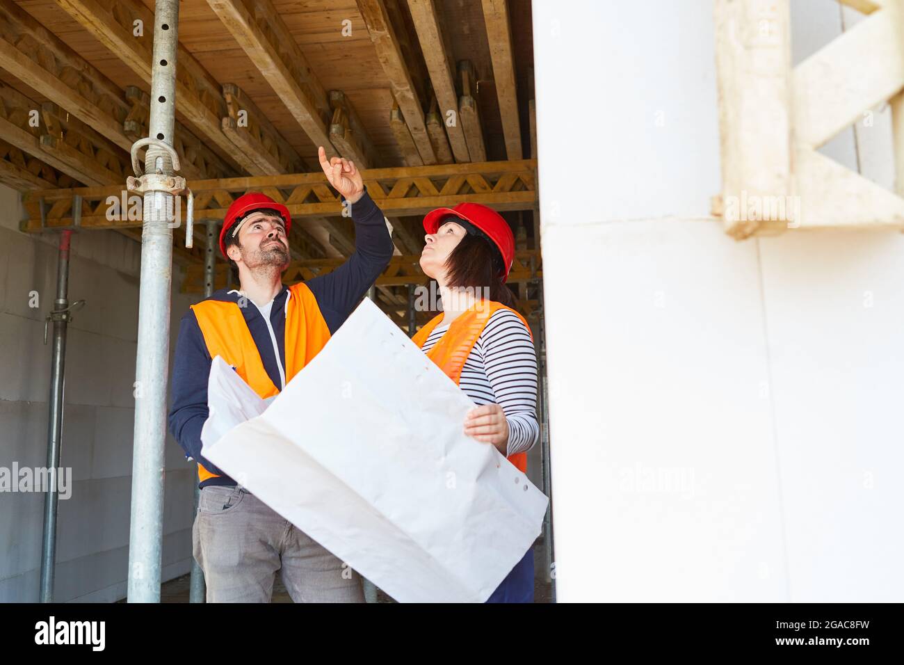 Architect with architectural drawing and carpenter look at the ...