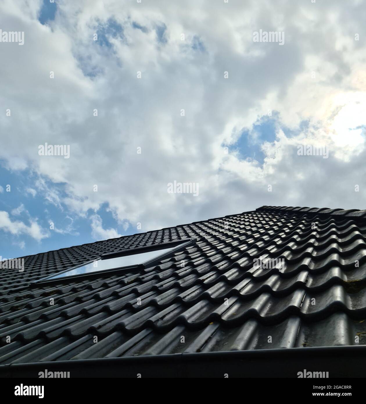 Open roof window in velux style with surrounding black roof tiles Stock ...