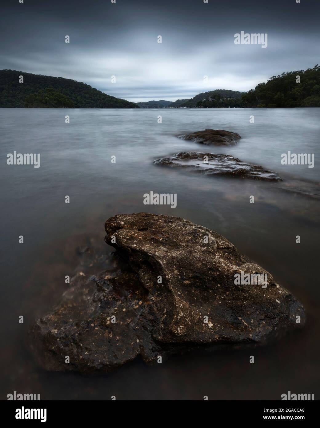 rocks in a large body of water surrounded by mountains Stock Photo - Alamy