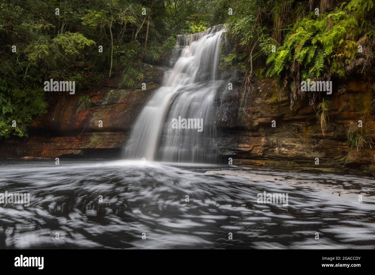 a waterfall with trees on the side of a river Stock Photo - Alamy