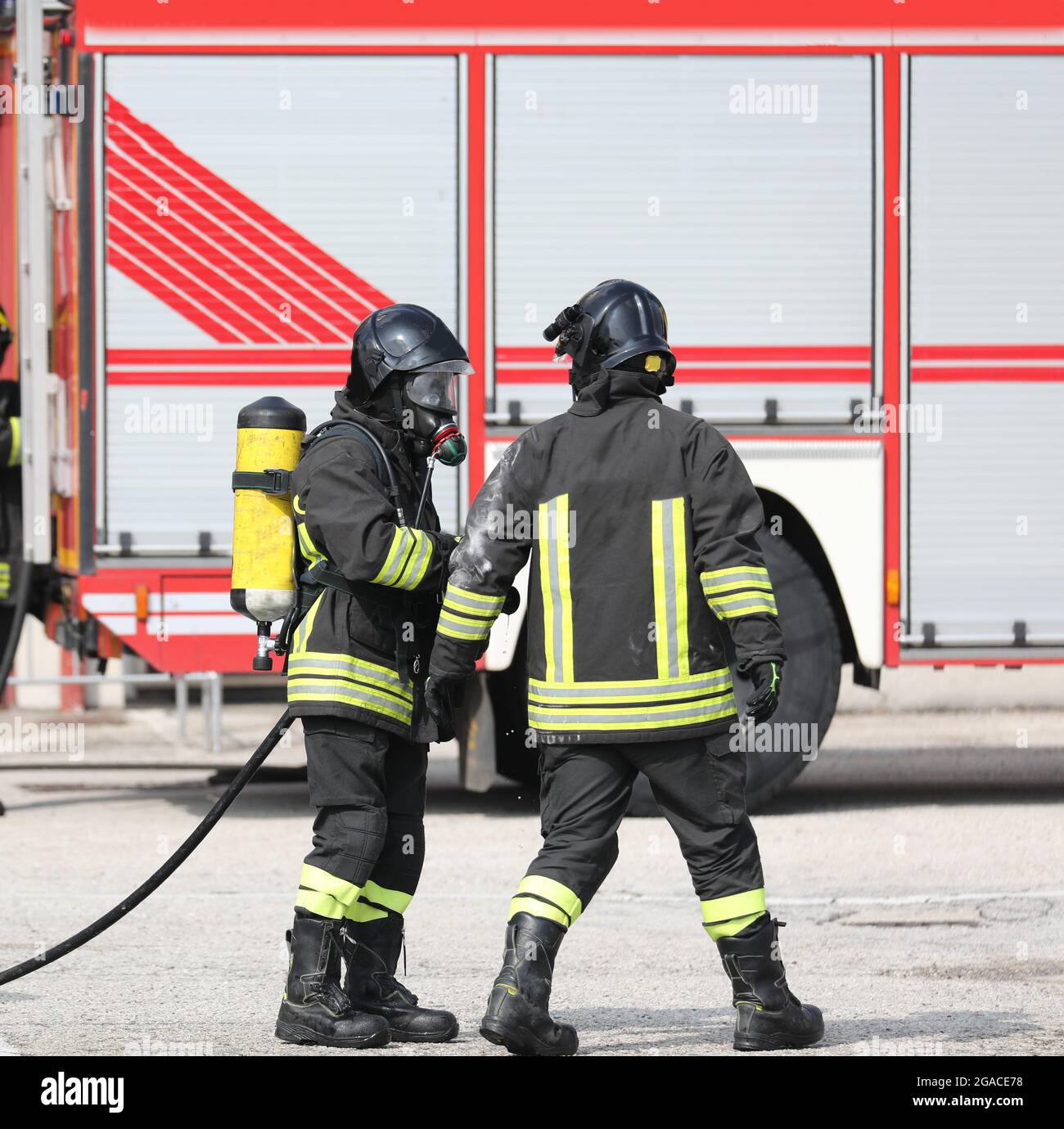 two firefighters in uniform with self-contained oxygen cylinder during ...