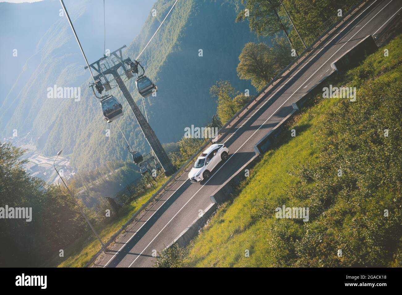 a car with tourists passes along a mountain road under the funicular ...