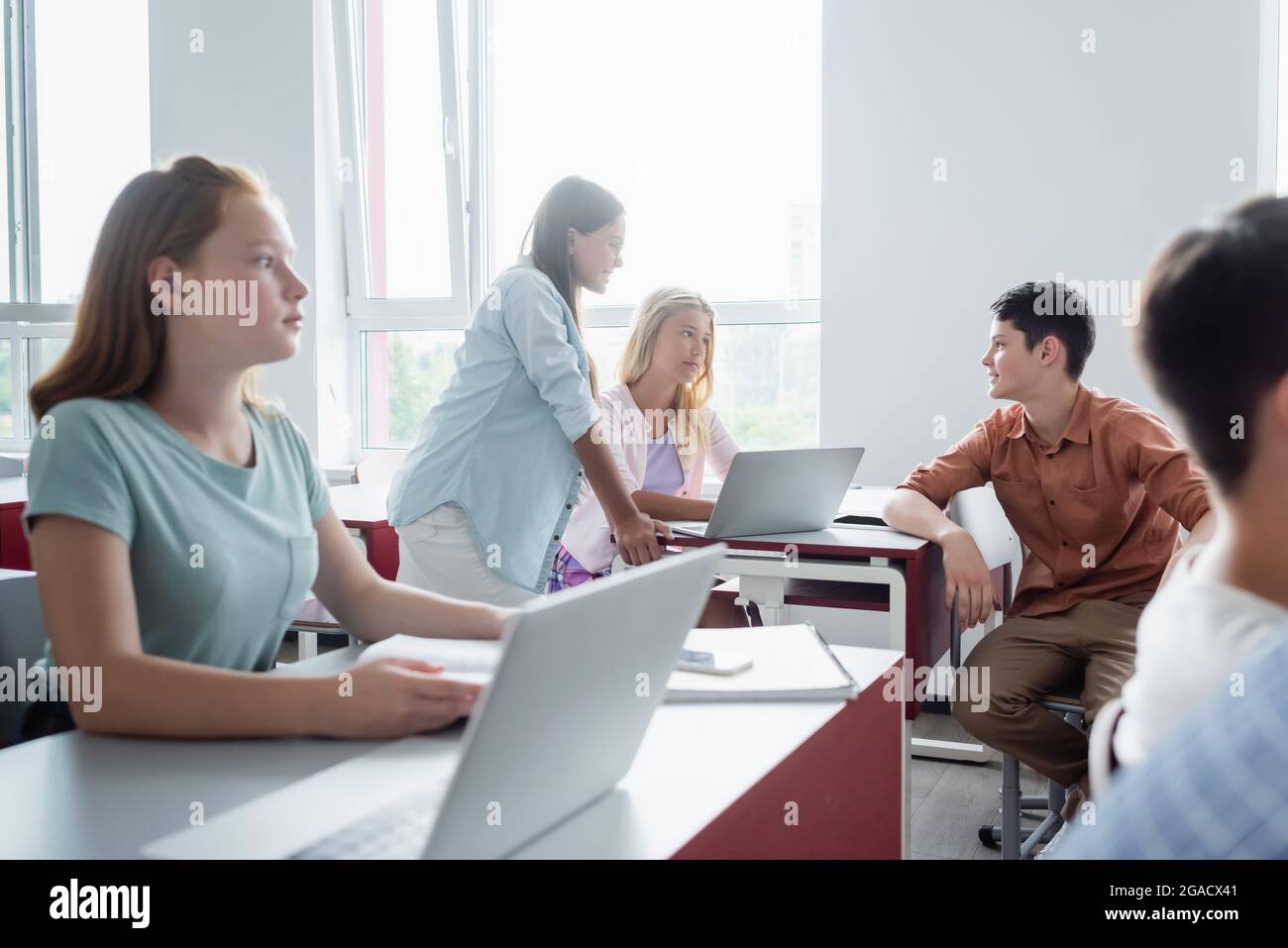 Schoolkids talking near devices and blurred friends in classroom Stock ...