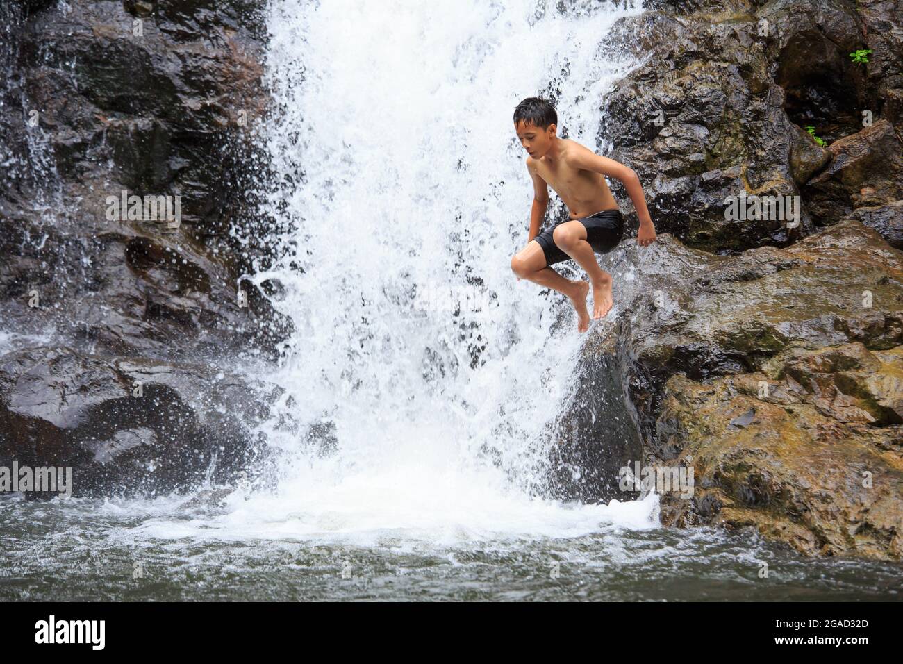 Boy jumping from rock into water in waterfall Stock Photo - Alamy