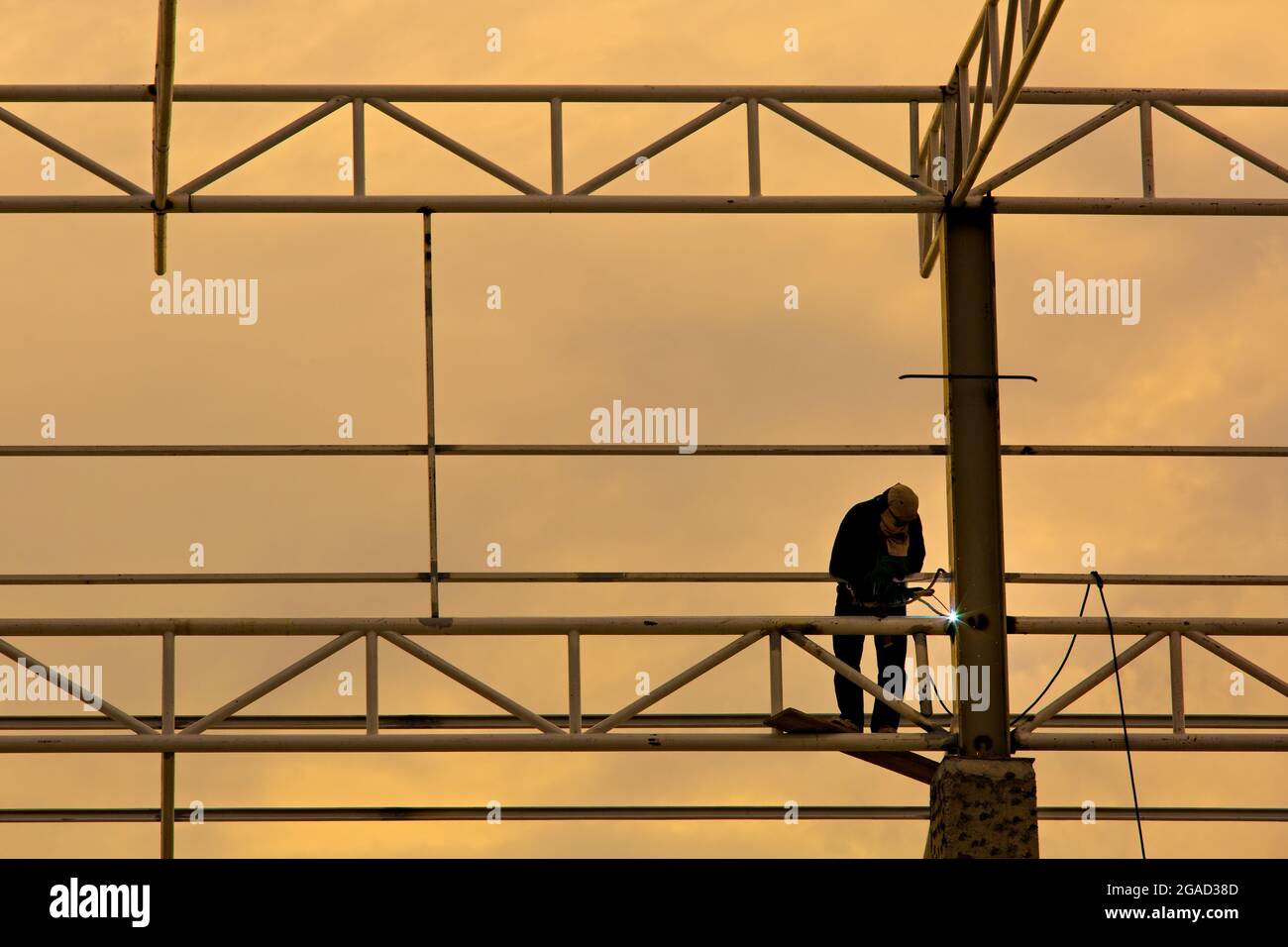 Worker working on high construction site at twilight Stock Photo - Alamy