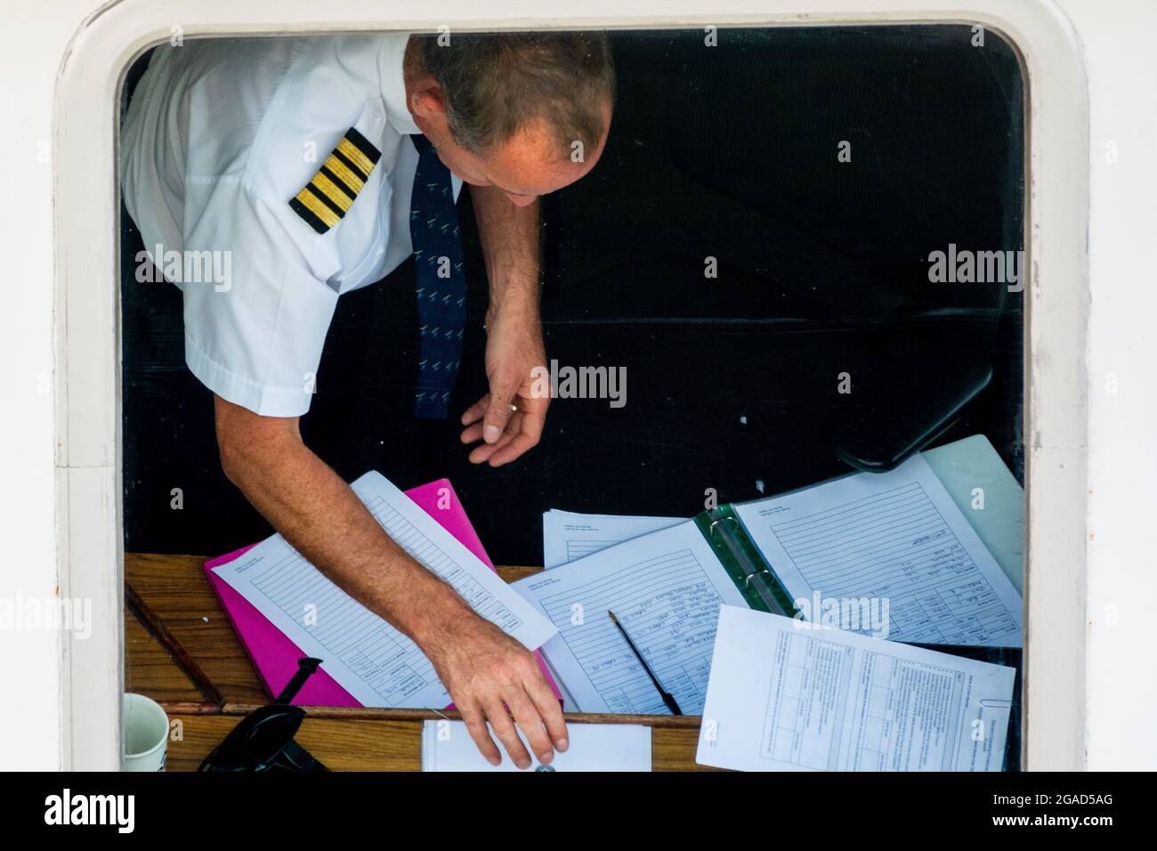 Ship captain looking at navigation papers and logistics documents prior ...