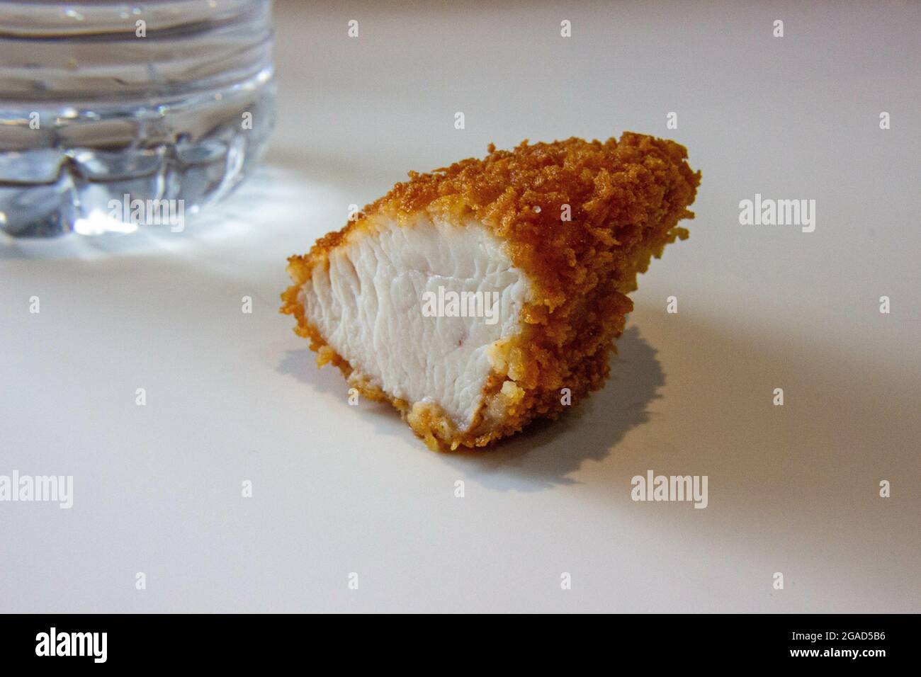 Closeup shot of a crispy chicken strip on a white table Stock Photo - Alamy