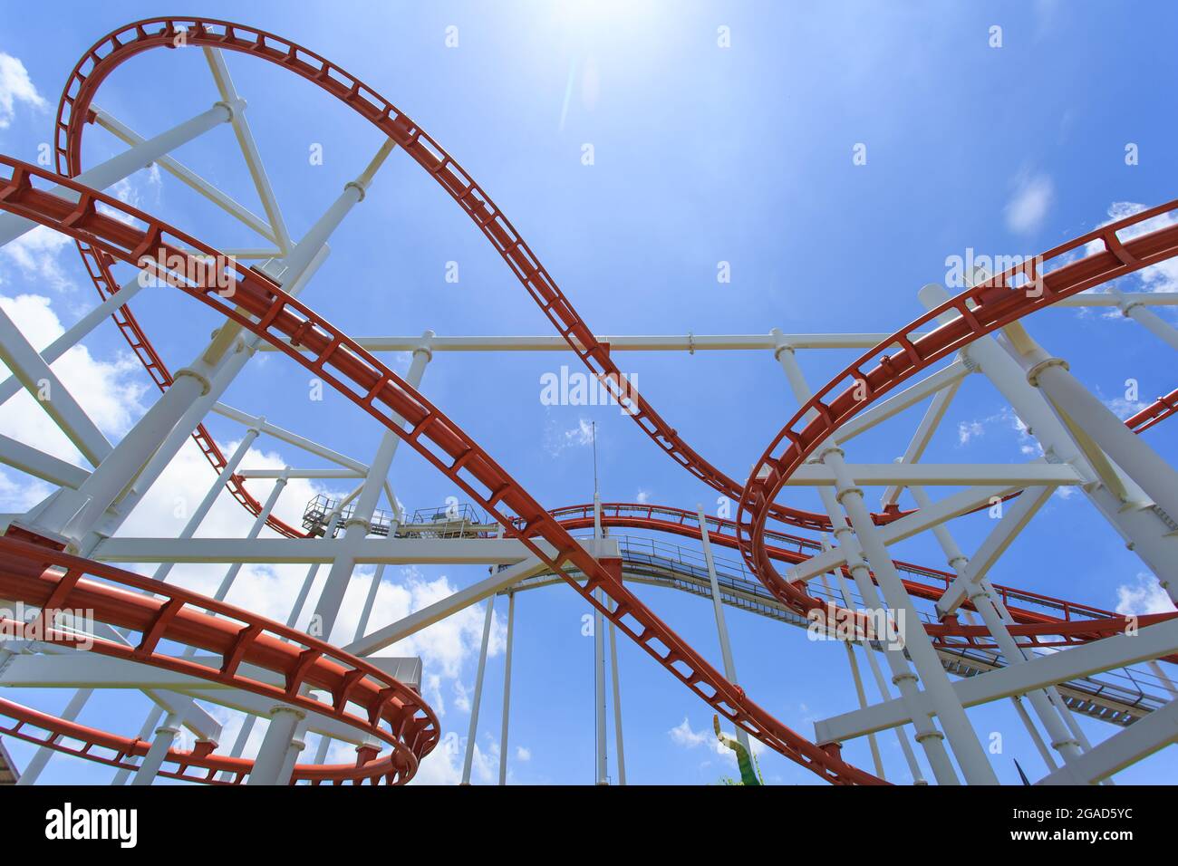 Red roller coaster line with blue sky in background Stock Photo - Alamy
