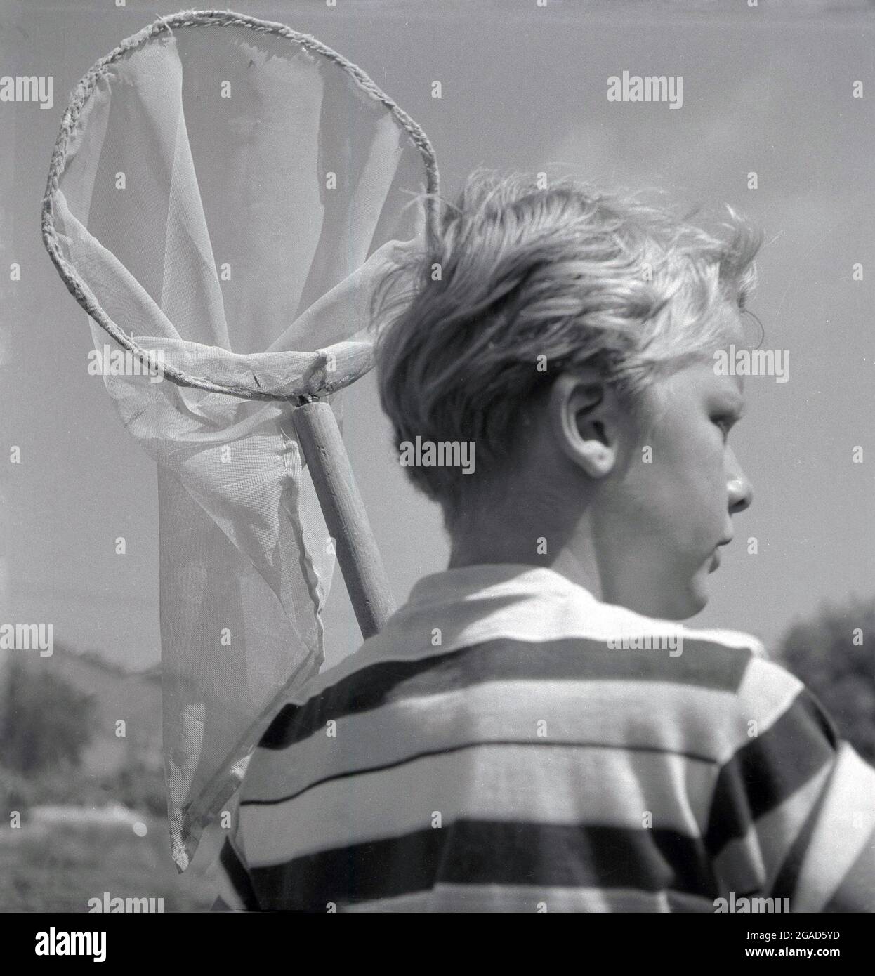 1960s, historical. summertime and outside in the countryside, a boy ...