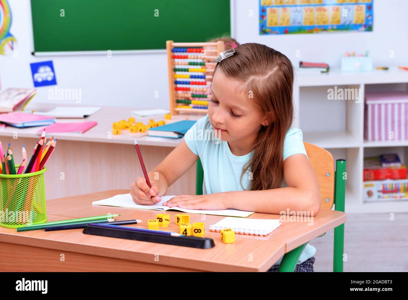 Little girl drawing at the desk in classroom Stock Photo - Alamy