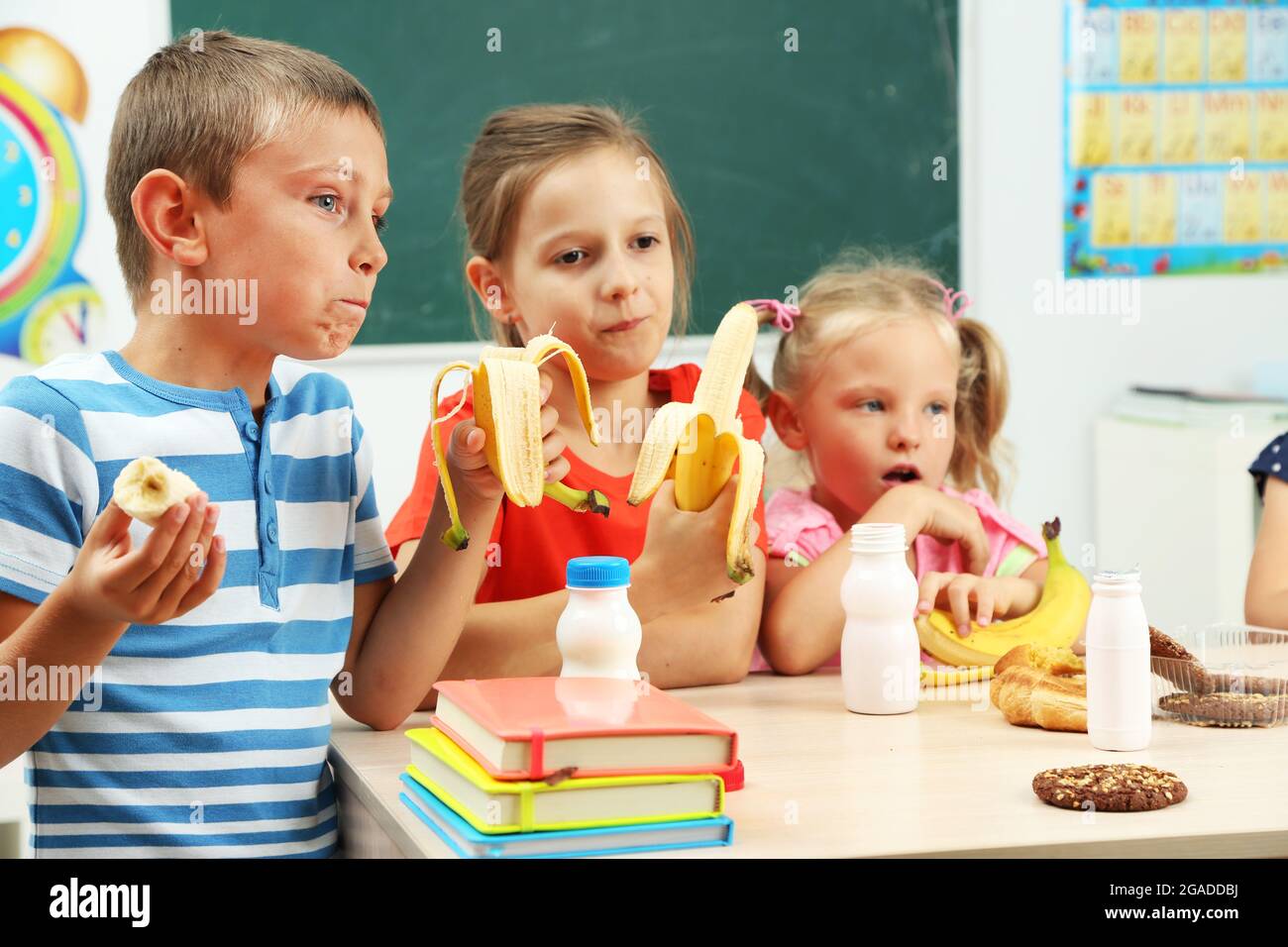 Cute children at lunch time in classroom Stock Photo - Alamy