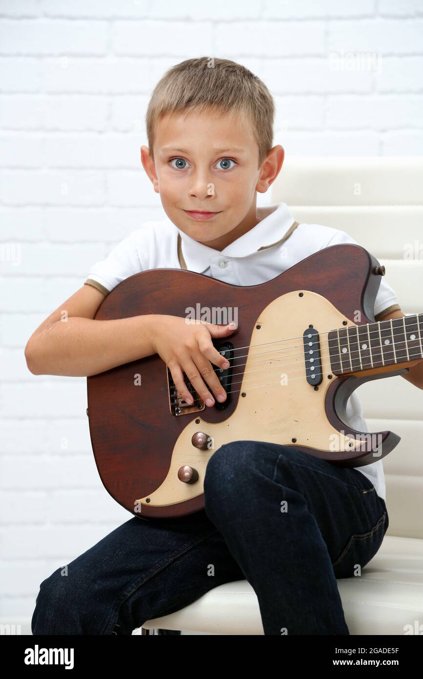 Little boy playing guitar on light background Stock Photo - Alamy
