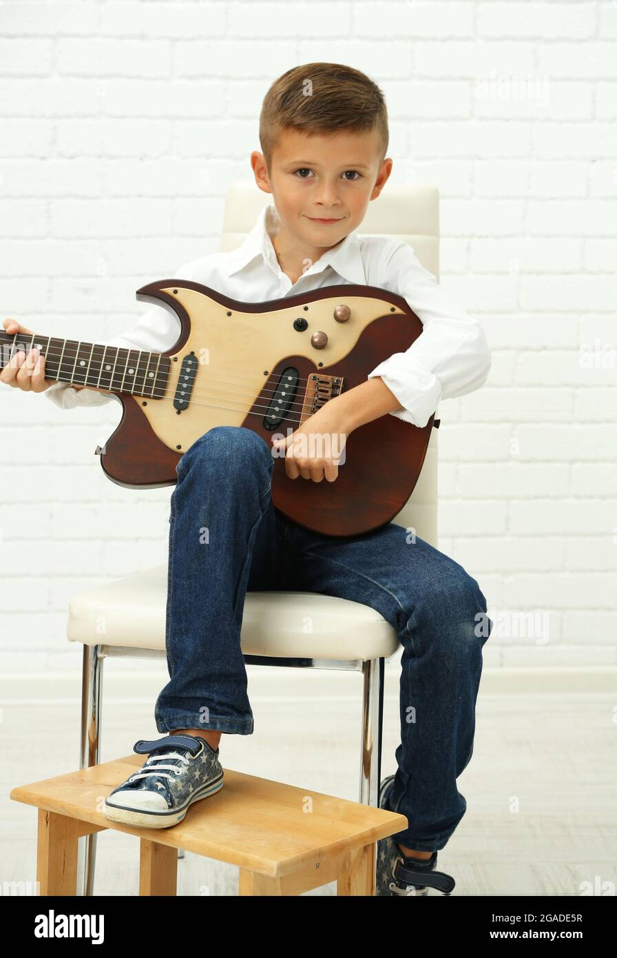 Little boy playing guitar on light background Stock Photo - Alamy