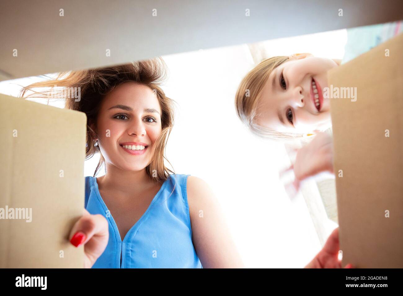 Excited mother and cute little daughter looking inside carton box ...