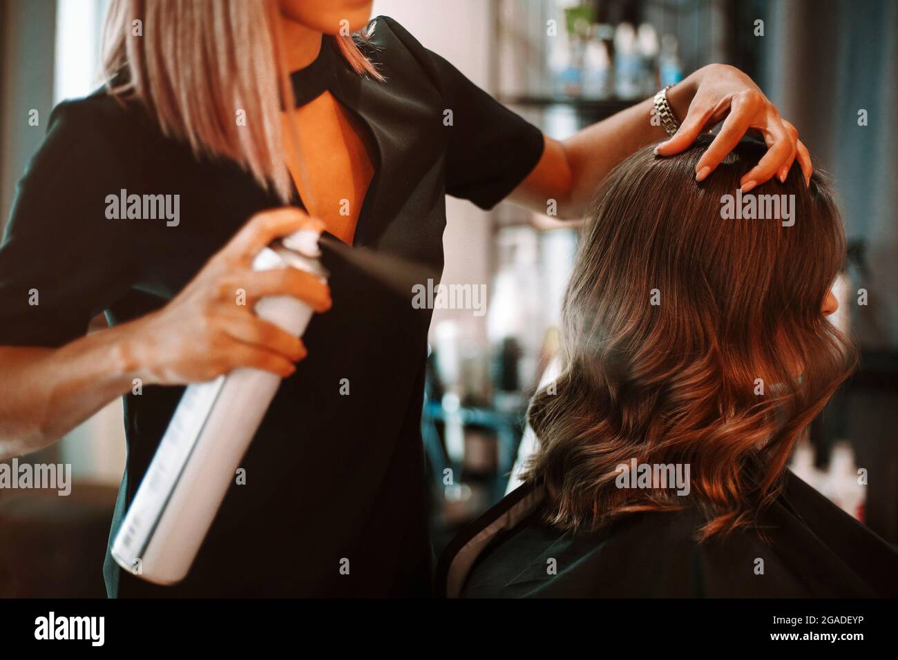 Hairstyling process in beauty salon. Cropped shot of female hairdresser ...