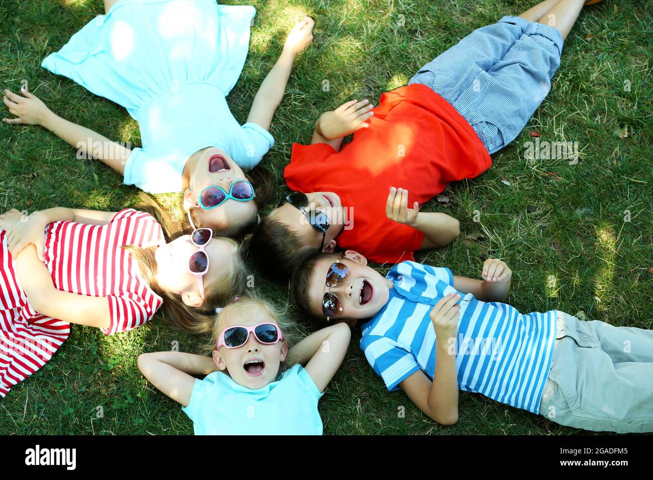 Happy active children lying on green grass in park Stock Photo - Alamy