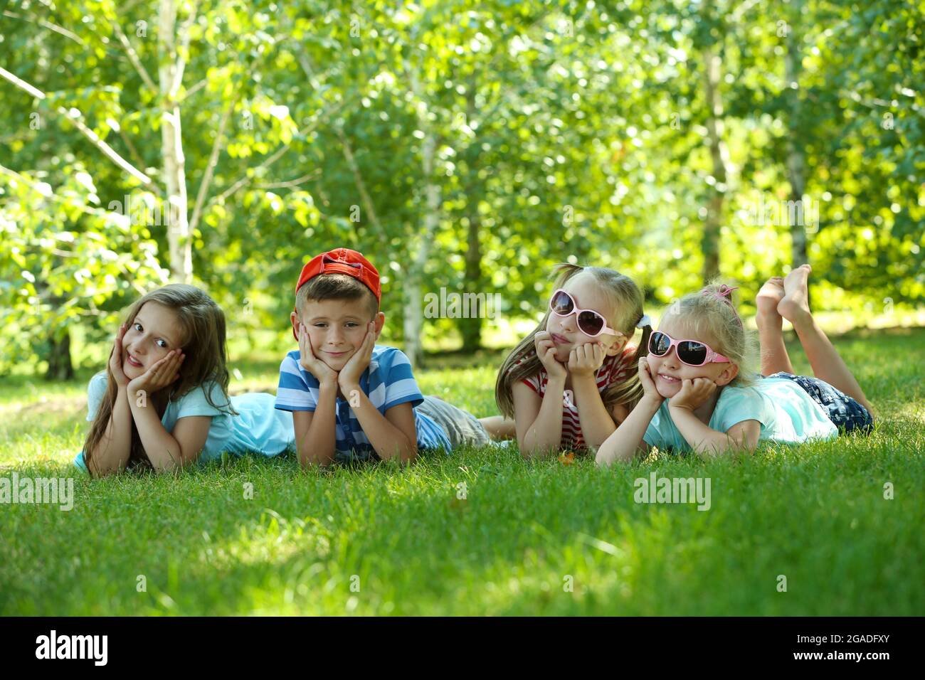 Happy active children lying on green grass in park Stock Photo - Alamy