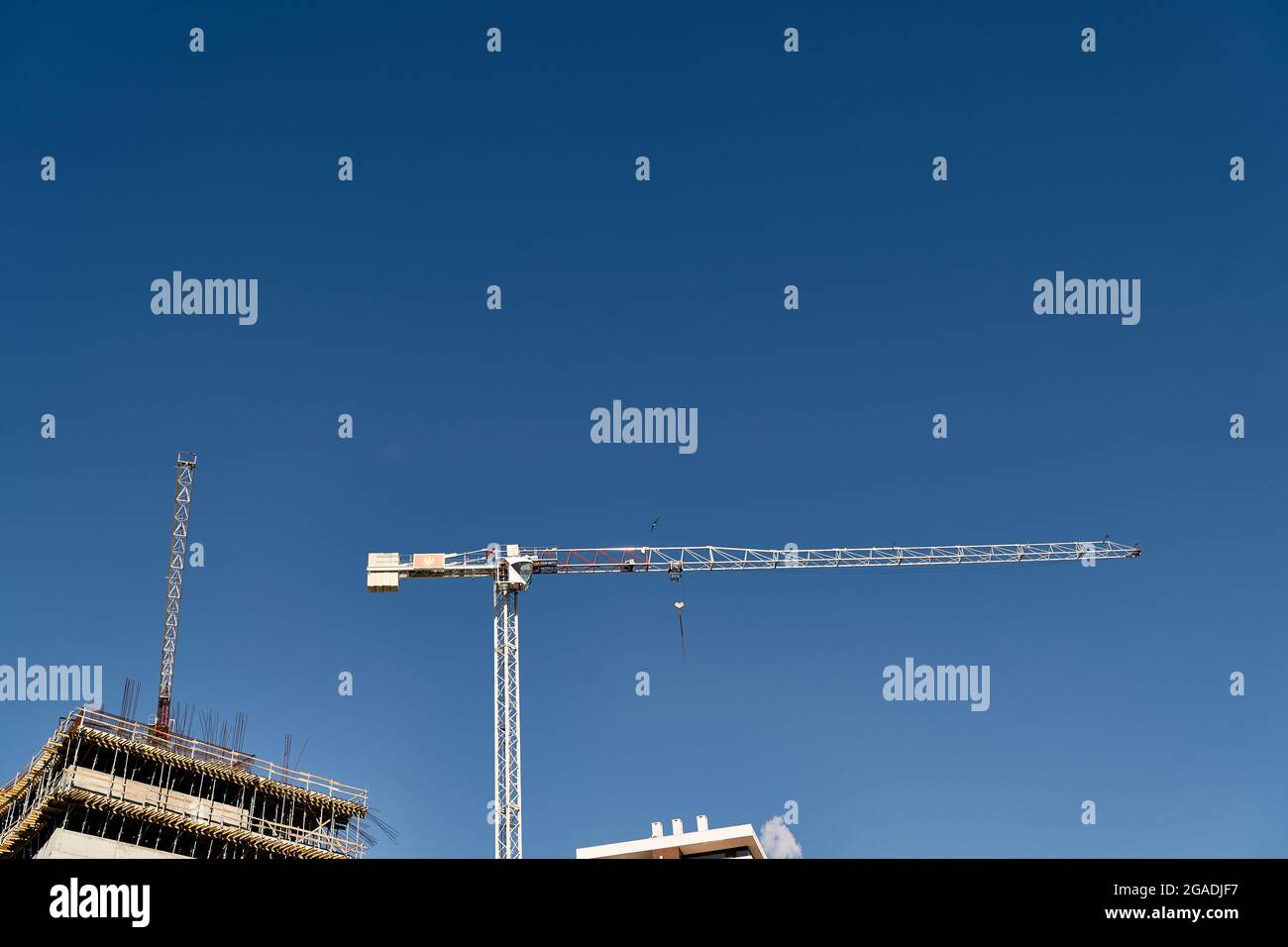 Tall construction crane towers over a construction site against a blue ...