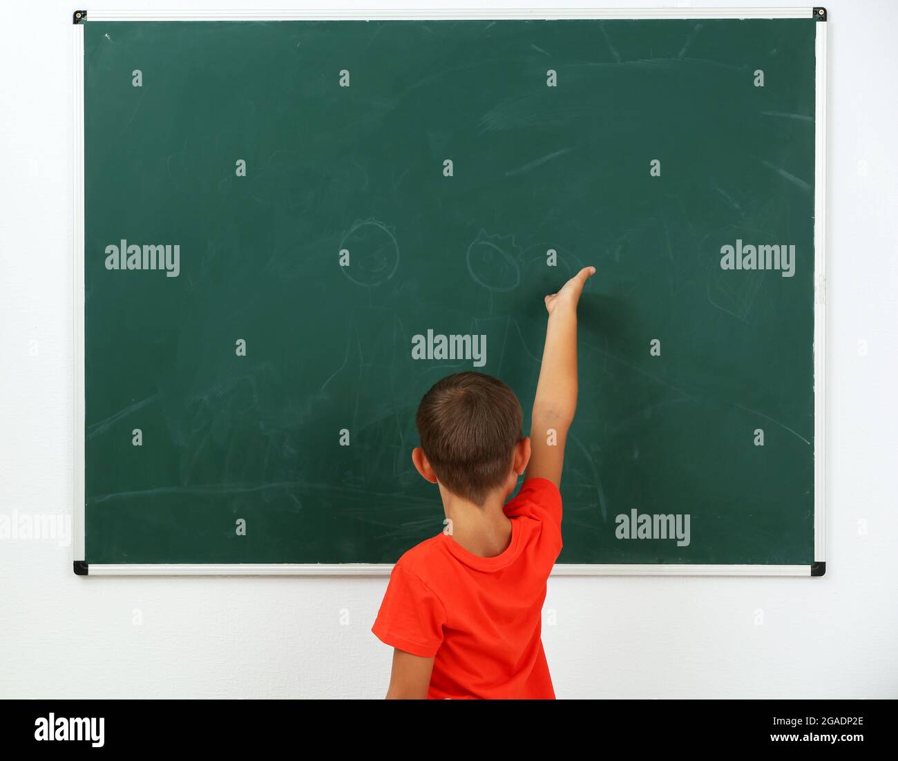 Little boy pointing at something at black chalkboard in classroom Stock ...