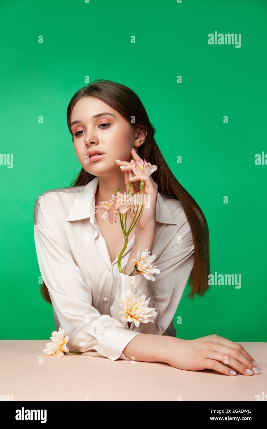 Crop female model with fresh flowers growing from blouse sleeves ...