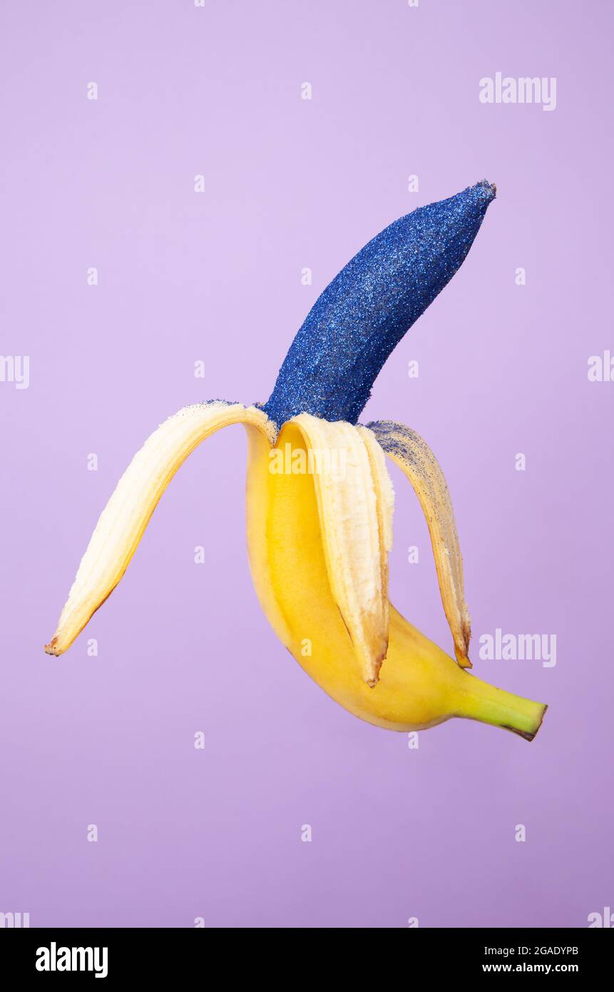 Peeled ripe banana covered with glittering paint of bright blue color ...