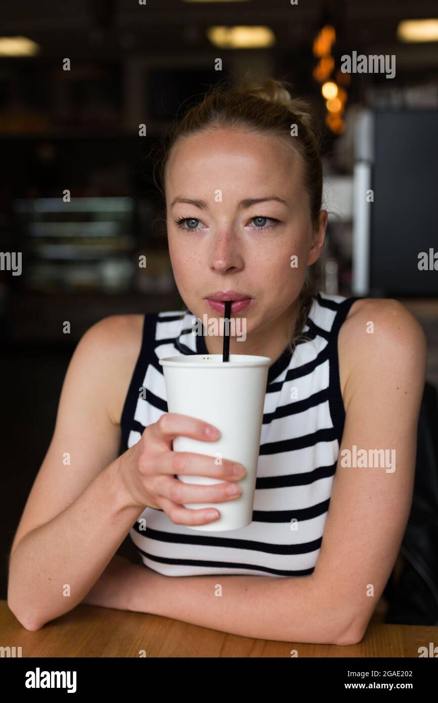 Young Caucasian Woman Sitting Alone In Coffee Shop Thoughtfully Leaning